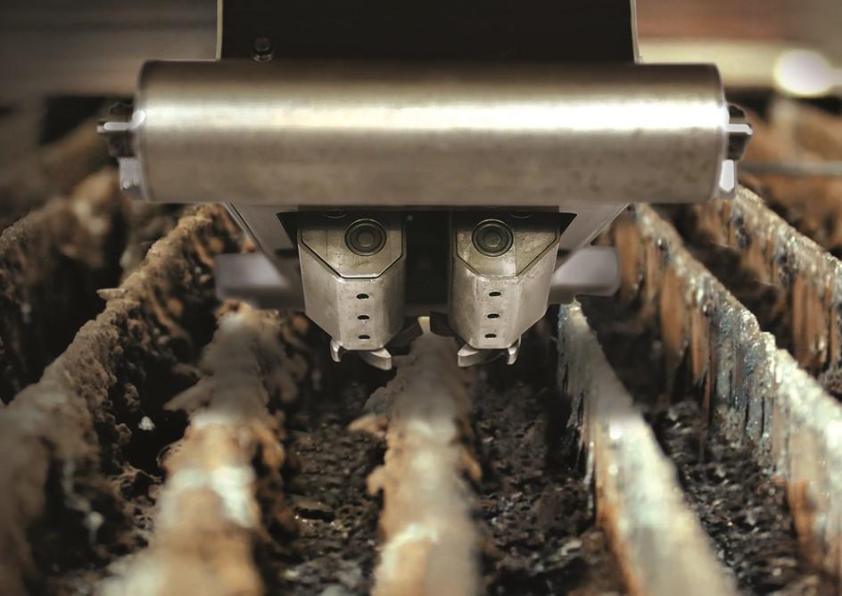 Machine cleans slag buildup from plasma cutting table slats